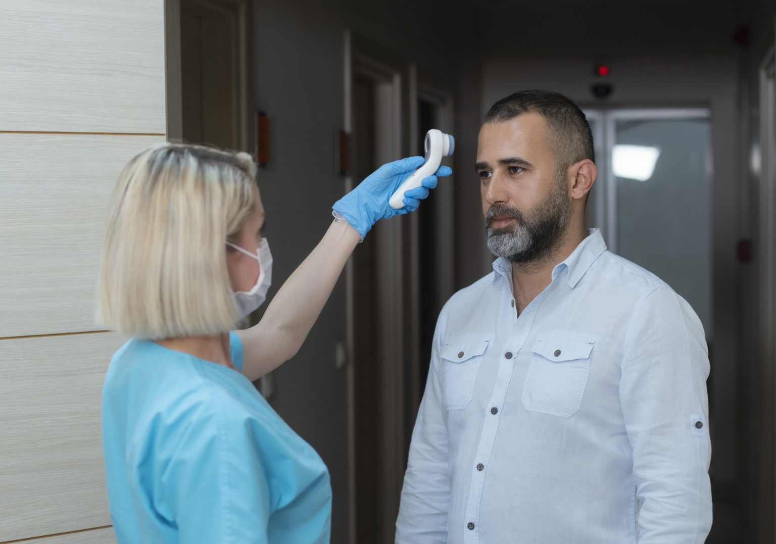 Female doctor checking temperature at patient with infrared tool in ...